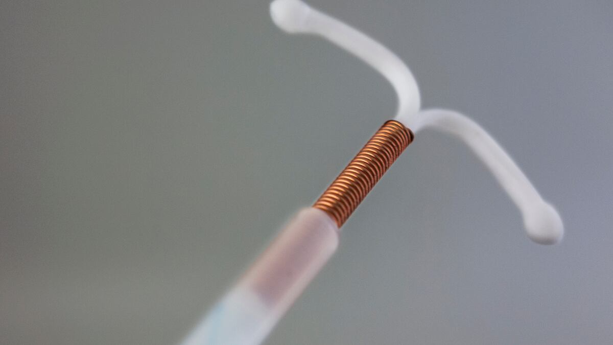 Newborn baby photographed with mother's IUD in hand